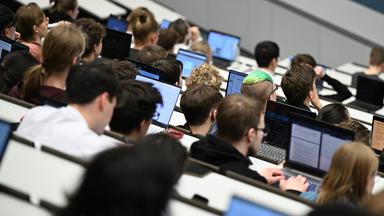 Studierende sitzen in einem Hörsaal an ihren Laptops.